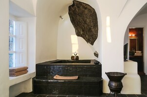 Casa de banho com uma banheira grande, lavatório e porta-toalhas.