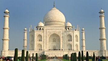 O Taj Mahal com quatro minaretes, uma cúpula central imponente e fachada simétrica.