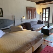 Quarto com cama grande, sofá, escrivaninha e janela.