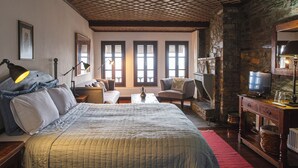 Um quarto aconchegante com uma cama grande, uma escrivaninha de madeira, uma cadeira e uma televisão.