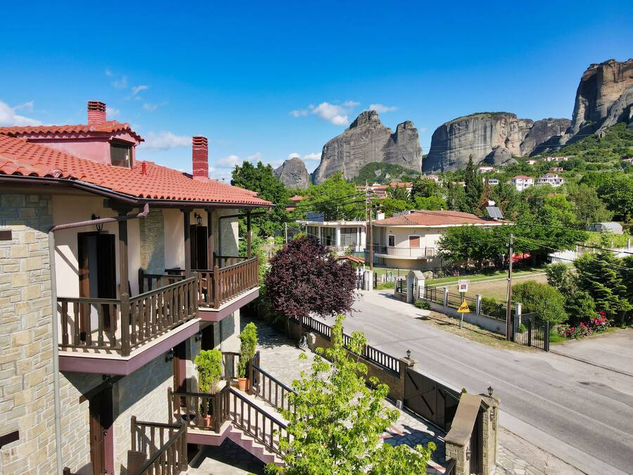 Uma área residencial com edifícios de pedra, telhado em tijolos vermelhos e uma rua que leva a um portão.