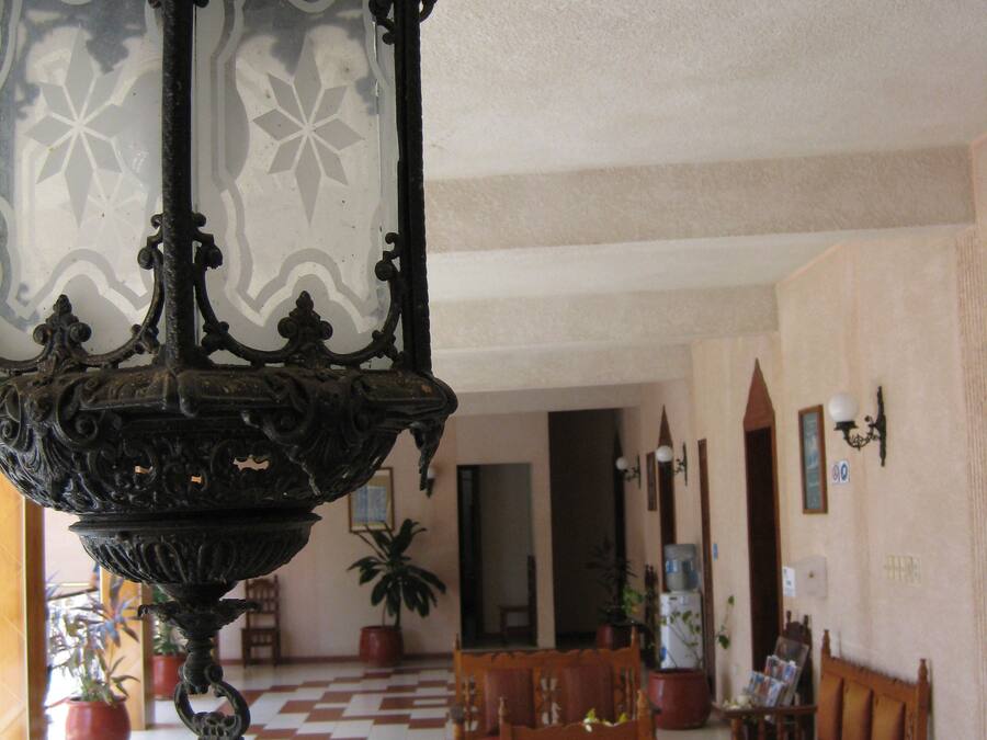 Um quarto amplo com piso quadriculado, móveis de madeira e um lustre ornamentado pendurado.