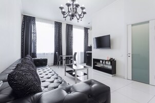 Uma sala de estar moderna com um sofá de couro, uma mesa de centro de vidro e um candelabro.