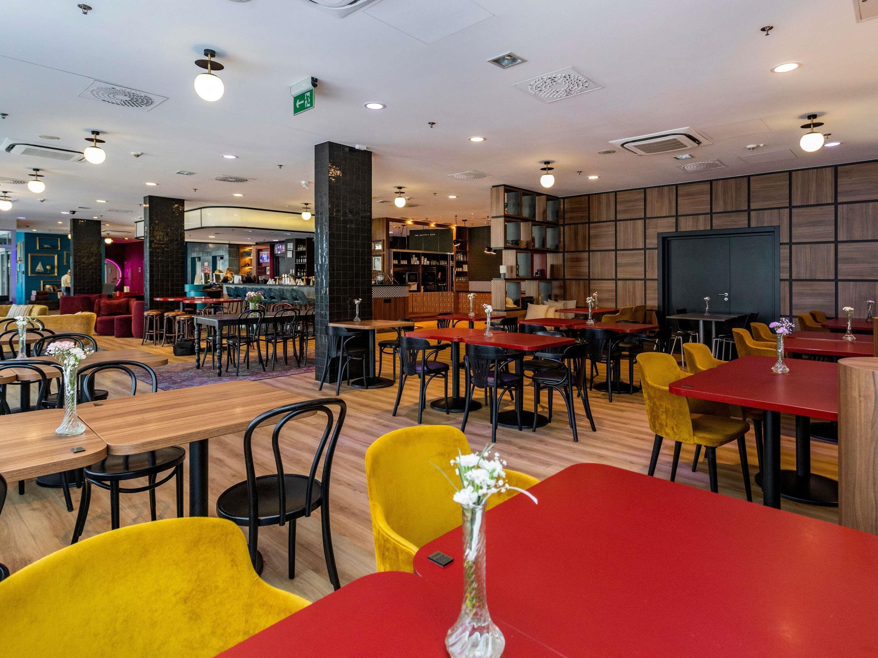 Restaurante moderno com várias áreas de refeição, incluindo um bar e um espaço com lareira.