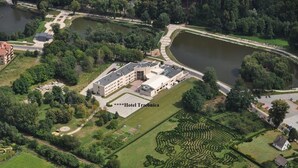 Vista aérea do Hotel Trzebonica com um amplo estacionamento, um pátio central e um lago próximo.