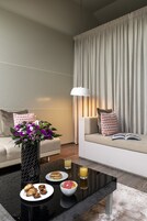 Uma sala de estar moderna com um sofá, uma mesa de centro com itens de café da manhã e um vaso decorativo.