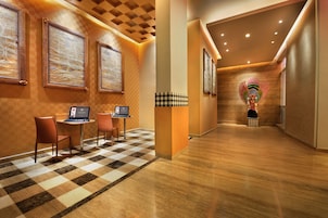 Um saguão de hotel com piso xadrez, obras de arte emolduradas nas paredes e uma escultura decorativa.