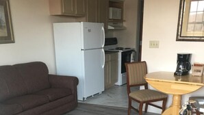 Um espaço compacto com cozinha compacta, sofá, mesa de jantar com cadeiras e cafeteira.