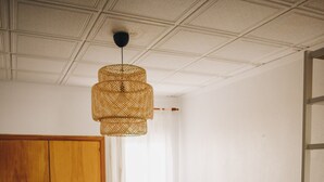 Quarto com cama, guarda-roupa, escrivaninha e luminária pendente.