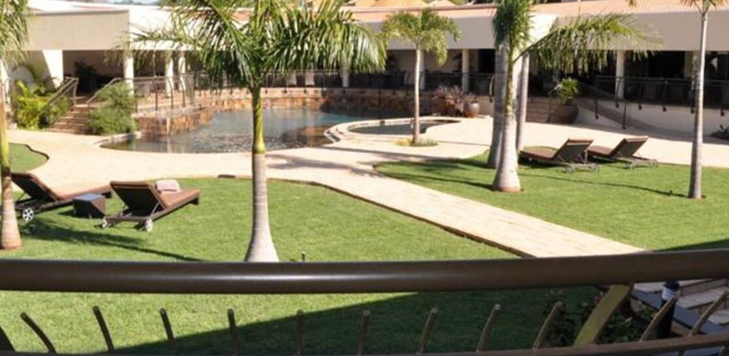 Uma área de piscina com espreguiçadeiras e palmeiras.