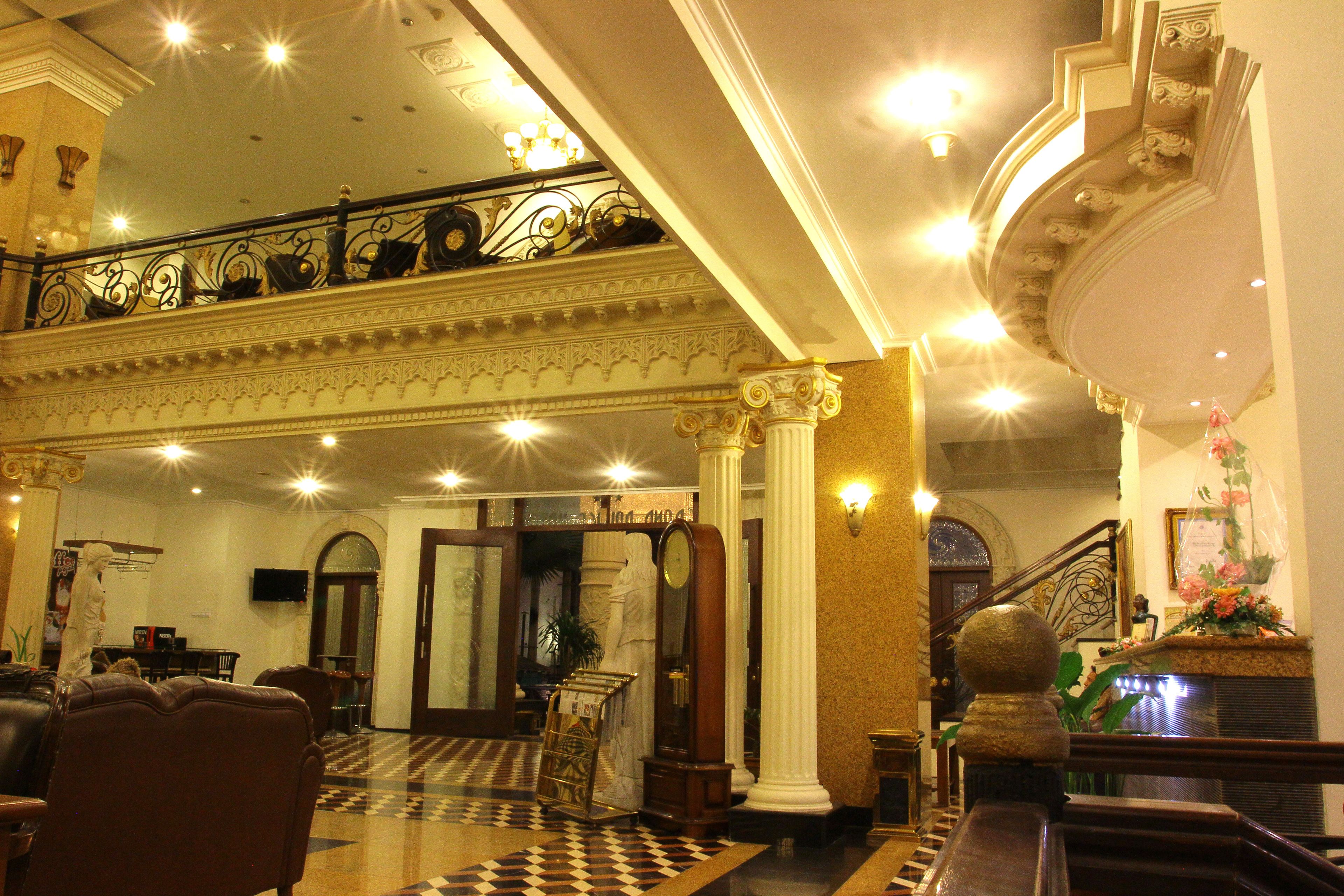Um amplo hall com piso xadrez, escada com grades ornamentadas e um espelho grande.