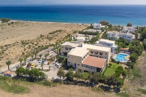 Uma área residencial costeira com edifícios modernos, uma piscina e uma praia ao fundo.
