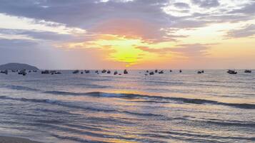 Uma praia com barcos e um pôr do sol.