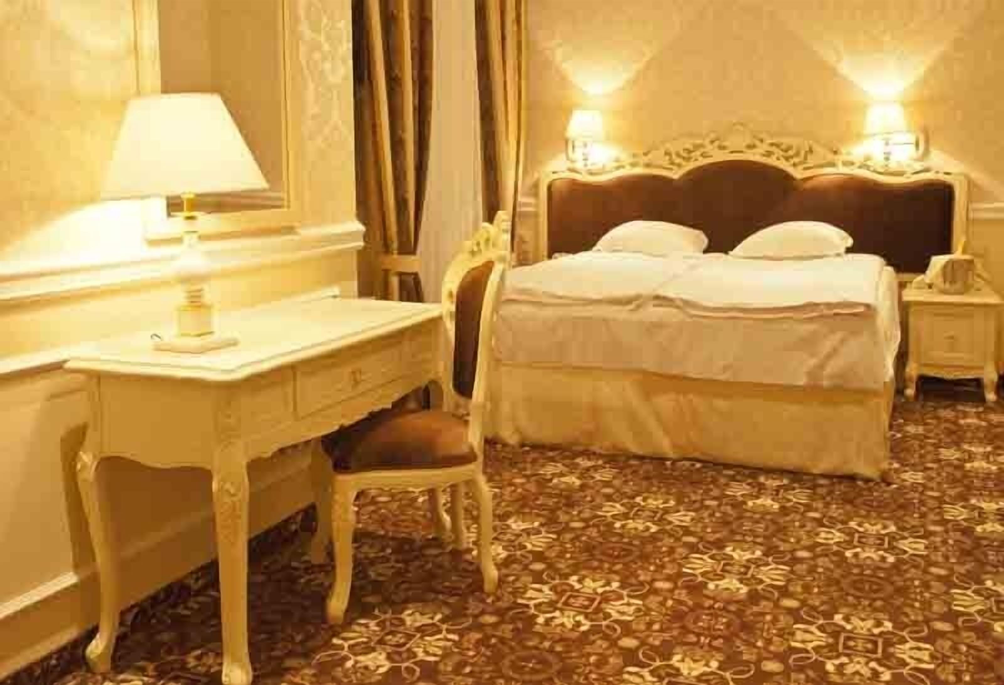 Quarto de hotel com cama, escrivaninha, cadeira e luminária.