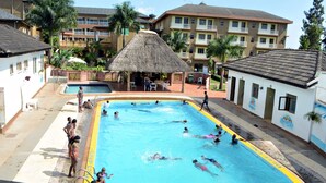 Piscina rodeada por edifícios com varandas e palmeiras.