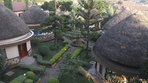 Um resort com edifícios de telhado de palha, jardins bem cuidados e um caminho central.