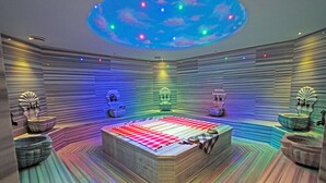 Quarto com uma cama grande, teto com desenho de nuvens e conchas decorativas nas paredes.