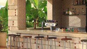 Uma área de bar com painel de azulejos, dispensador de Pepsi e diversas garrafas.