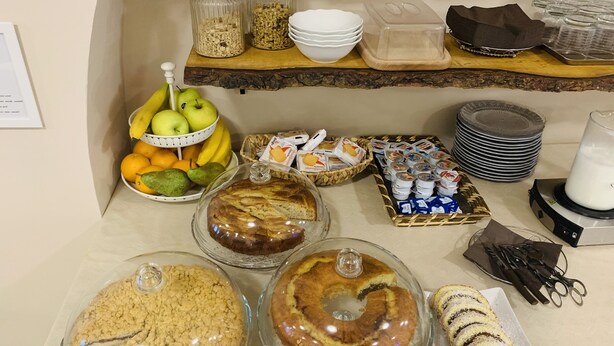Disposição de buffet com diversos alimentos, incluindo frutas, sobremesas e bebidas.