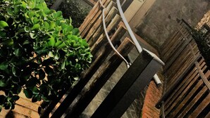 Uma escadaria com corrimão de metal, cercada por paredes de tijolo e plantas em vasos.
