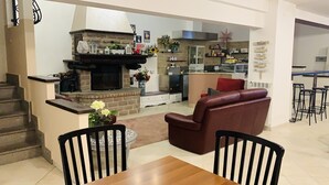 Uma sala de estar aconchegante com lareira, uma área de jantar com mesa e cadeiras, e uma cozinha ao fundo.