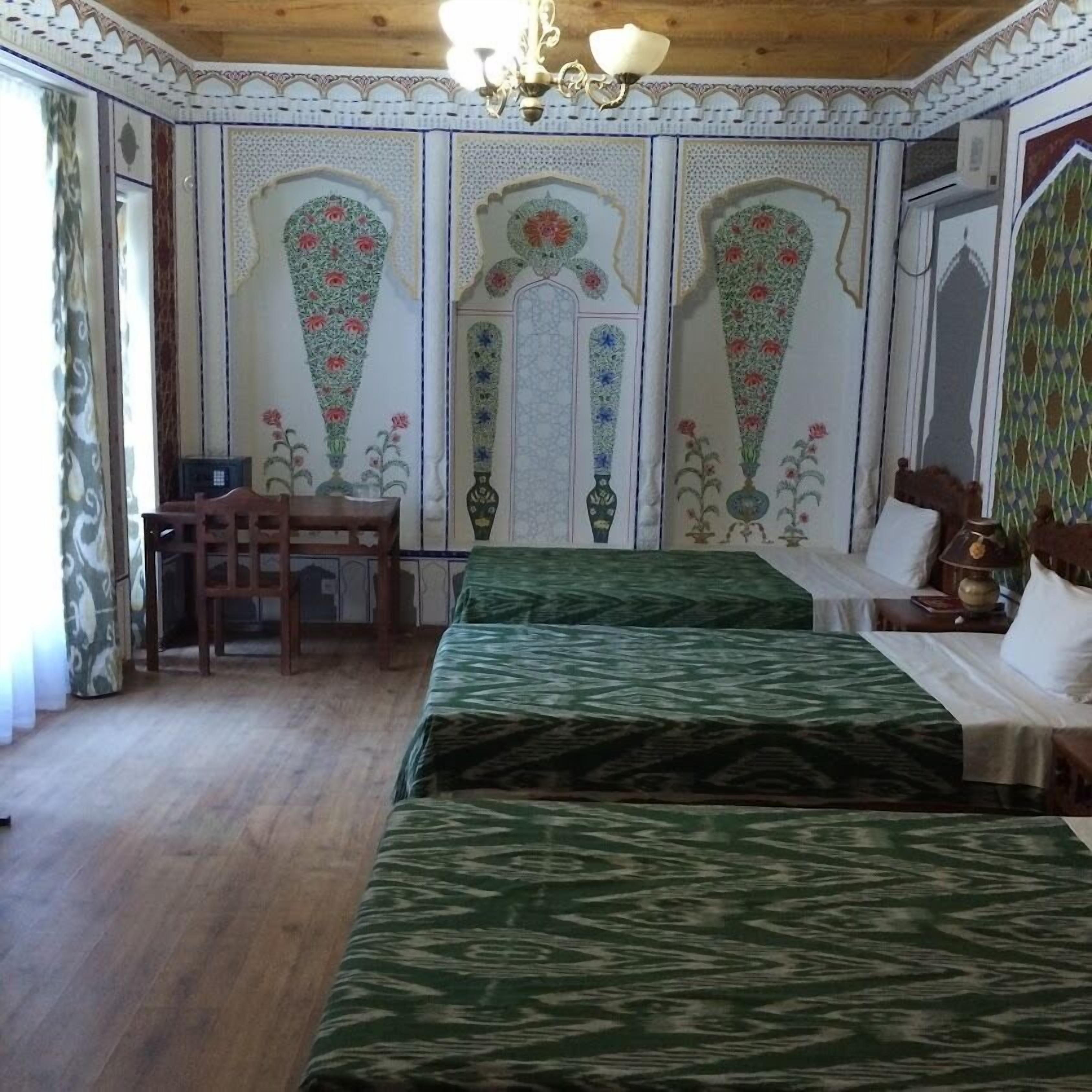 Quarto com duas camas, uma escrivaninha de madeira e um candelabro.