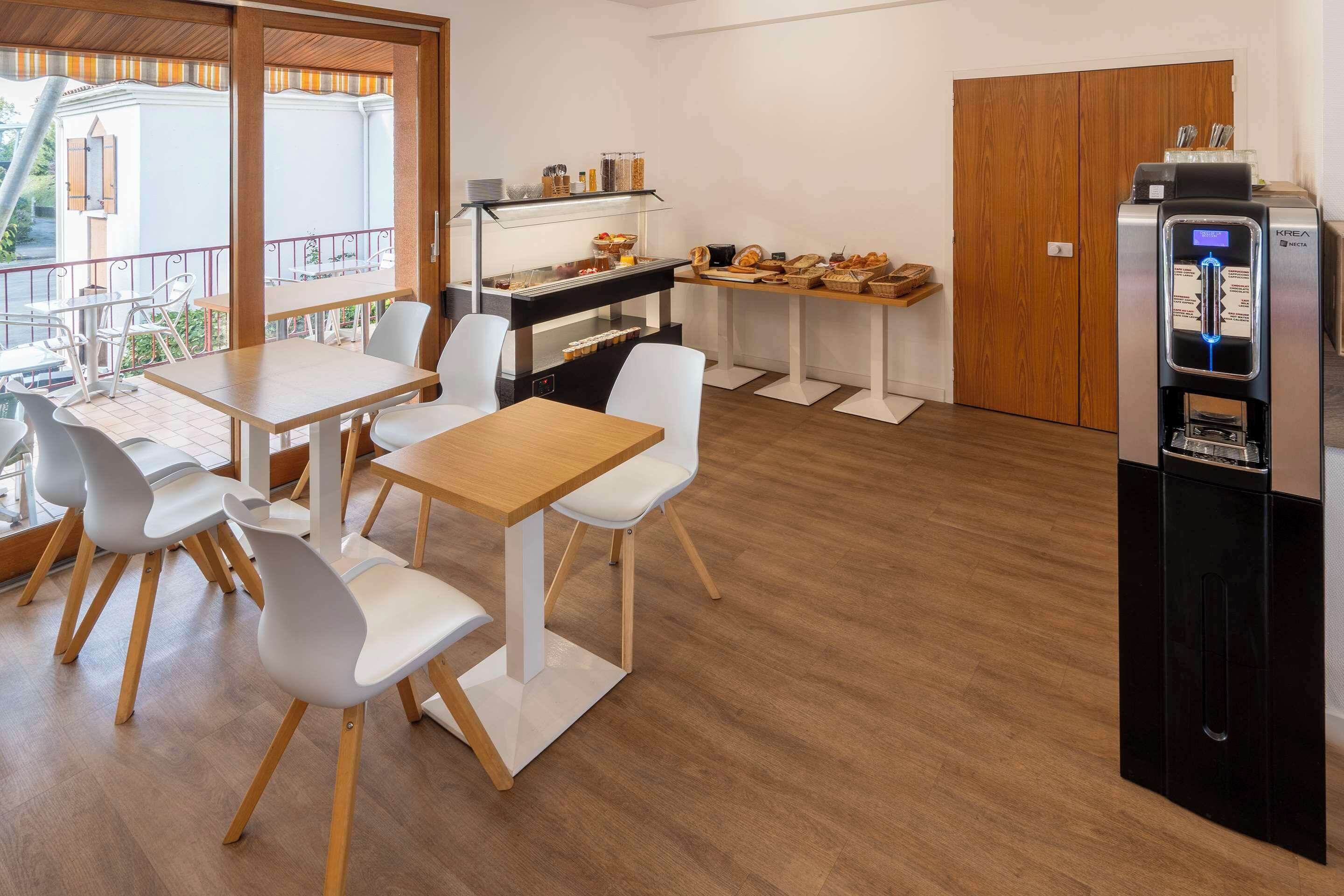 Espaço de café da manhã moderno com máquina de café, bancada para refeições e assentos.