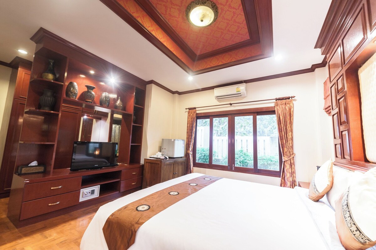 Quarto de hotel com uma cama grande, móveis de madeira, televisão e aparelho de ar condicionado.