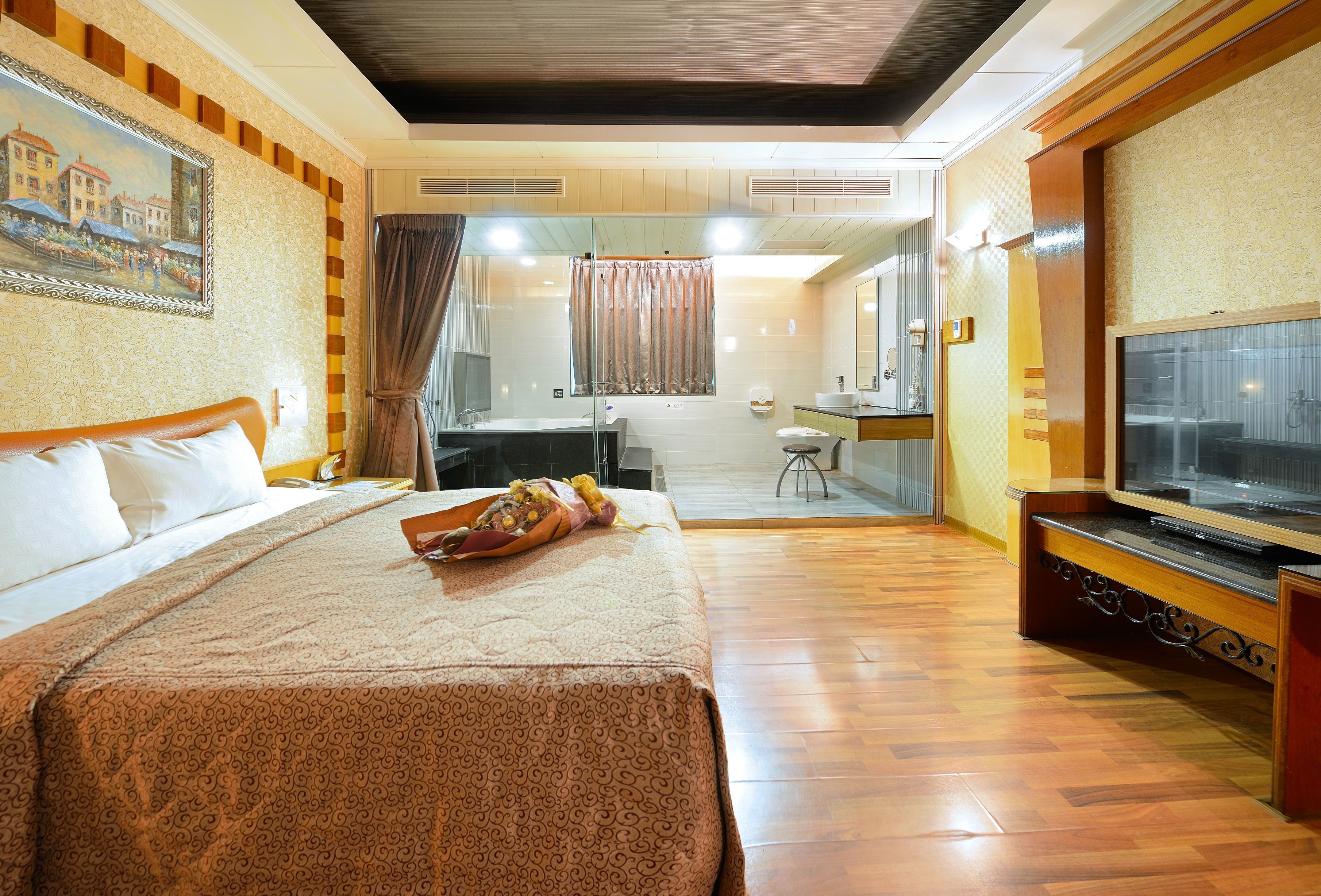 Quarto de hotel com cama, televisão, banheiro e área de refeições.