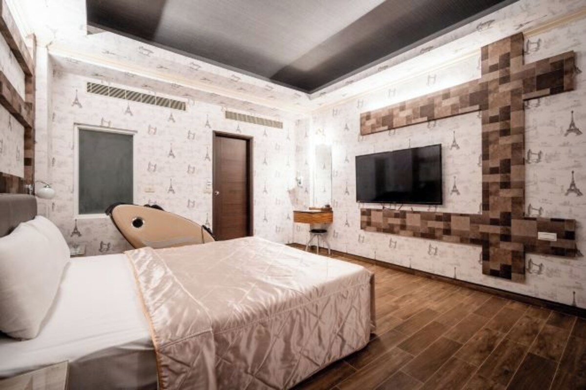 Quarto com cama, televisão, cadeira e escrivaninha.