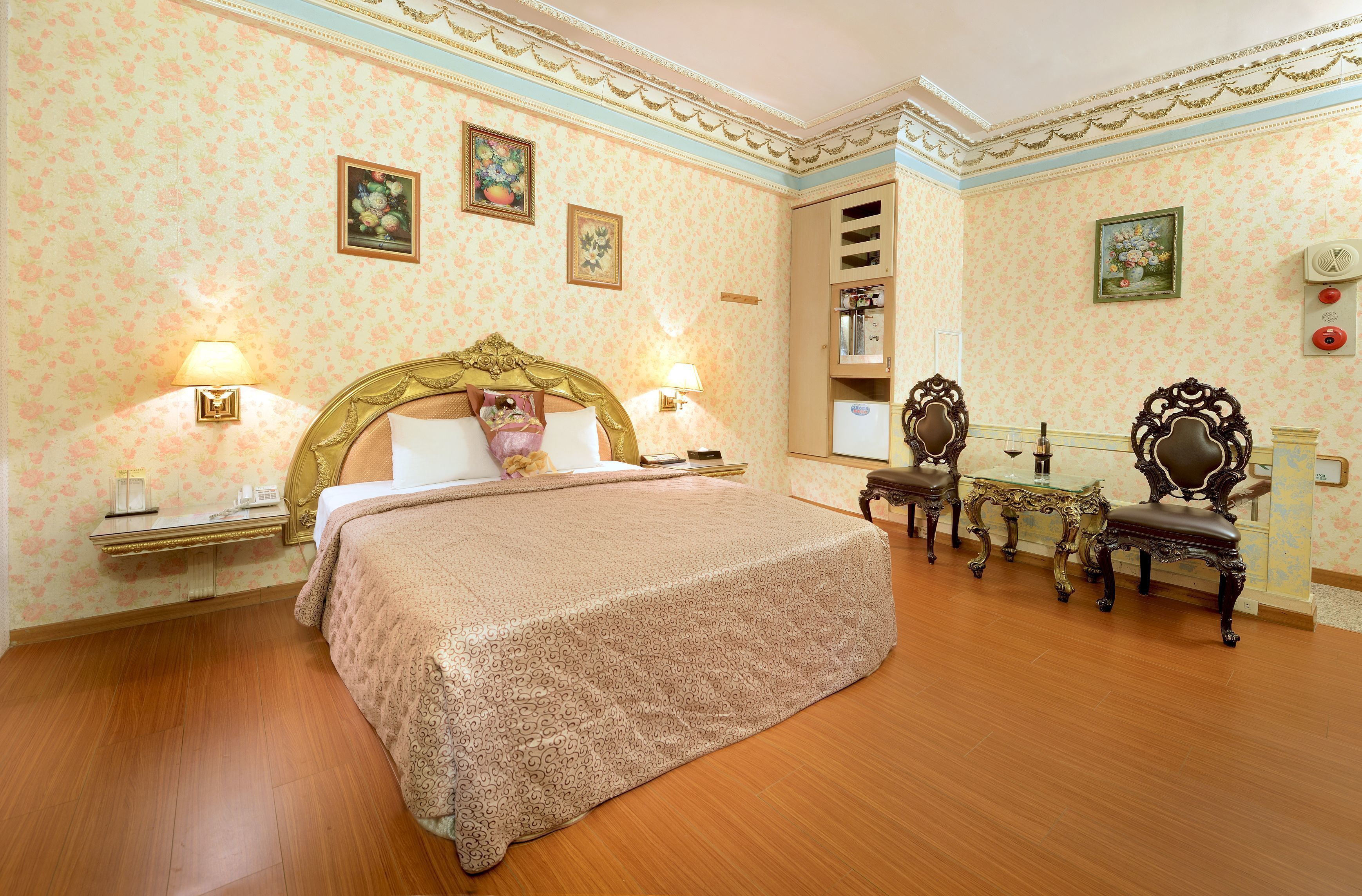 Quarto de hotel com uma cama grande, duas mesinhas de cabeceira, um penteado e um espelho.