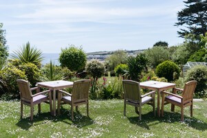 Um jardim com mesa e cadeiras, cercado por diversas plantas e flores.