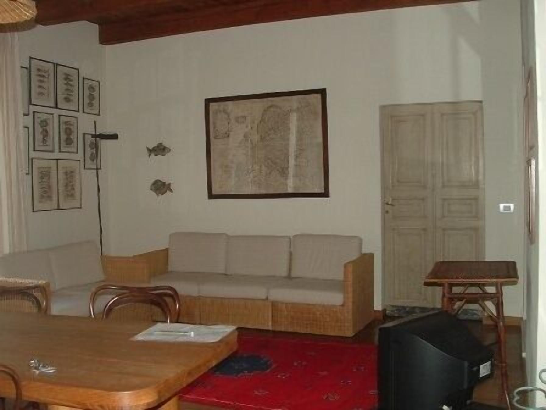 Uma sala de estar com sofá, mesa de madeira, televisão e quadros na parede.