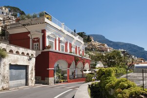 Um edifício vermelho e branco com varanda, janelas em arco e uma placa que diz "Saras".