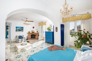 Quarto espaçoso com cama grande, lareira, penteadeira azul e vista para a cidade.