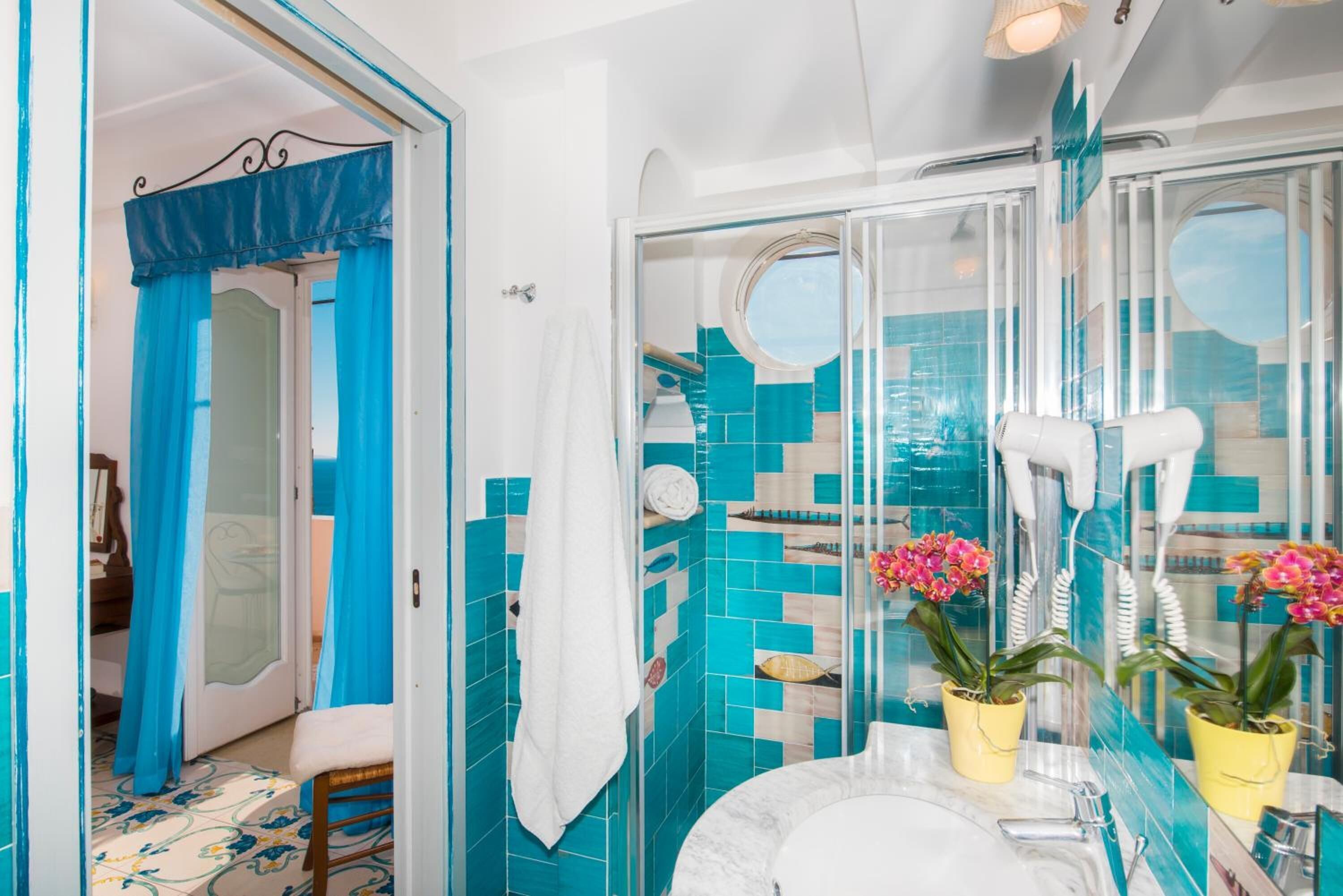 Casa de banho com cabine de duche em vidro, uma sanita branca e azulejos azuis nas paredes.