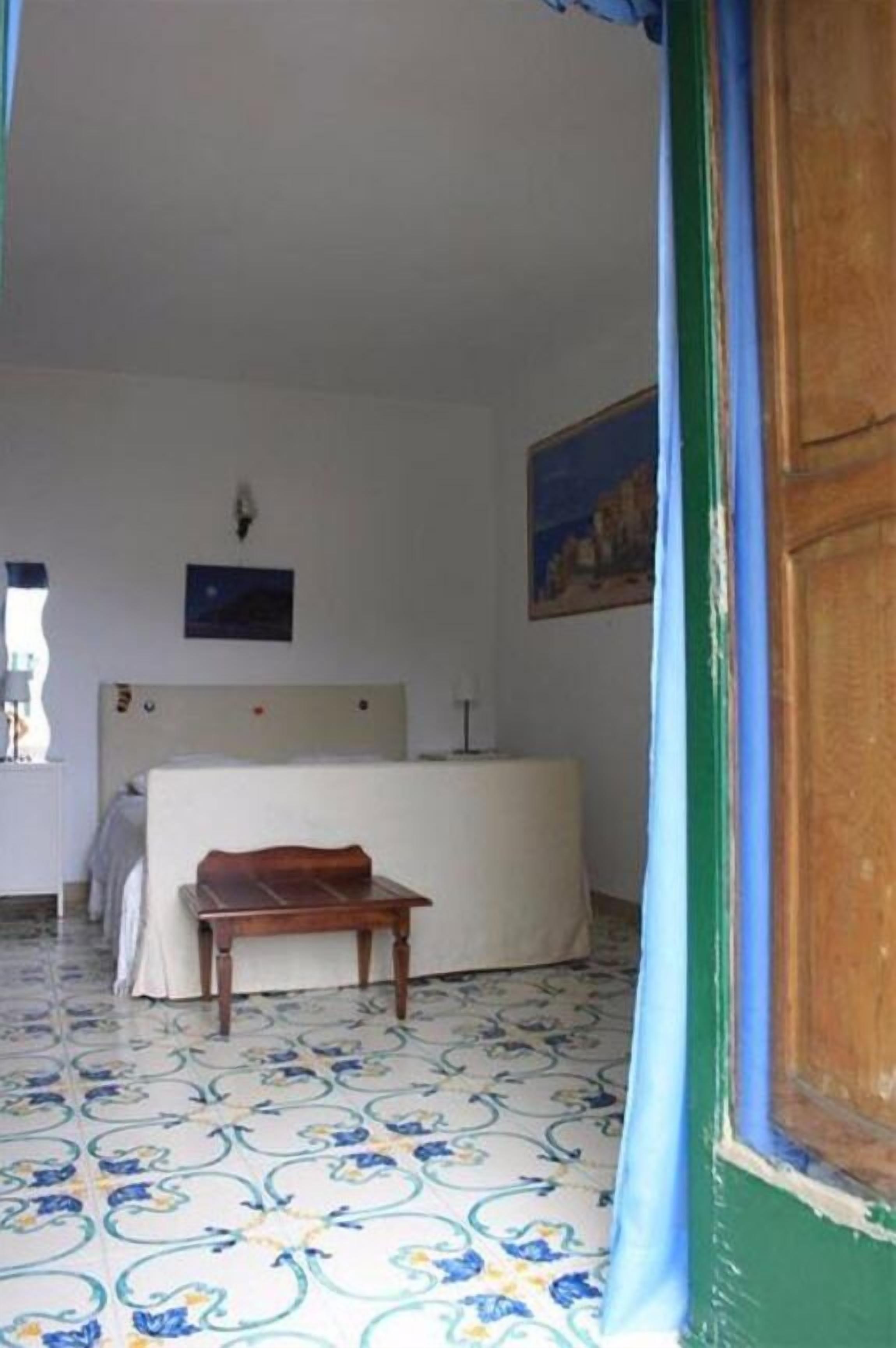 Um quarto com uma cama, uma mesinha e um quadro na parede.