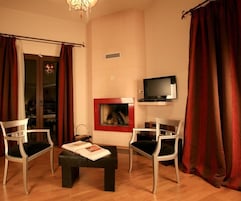 Uma sala de estar com lareira, duas poltronas, uma mesa de centro e uma televisão.