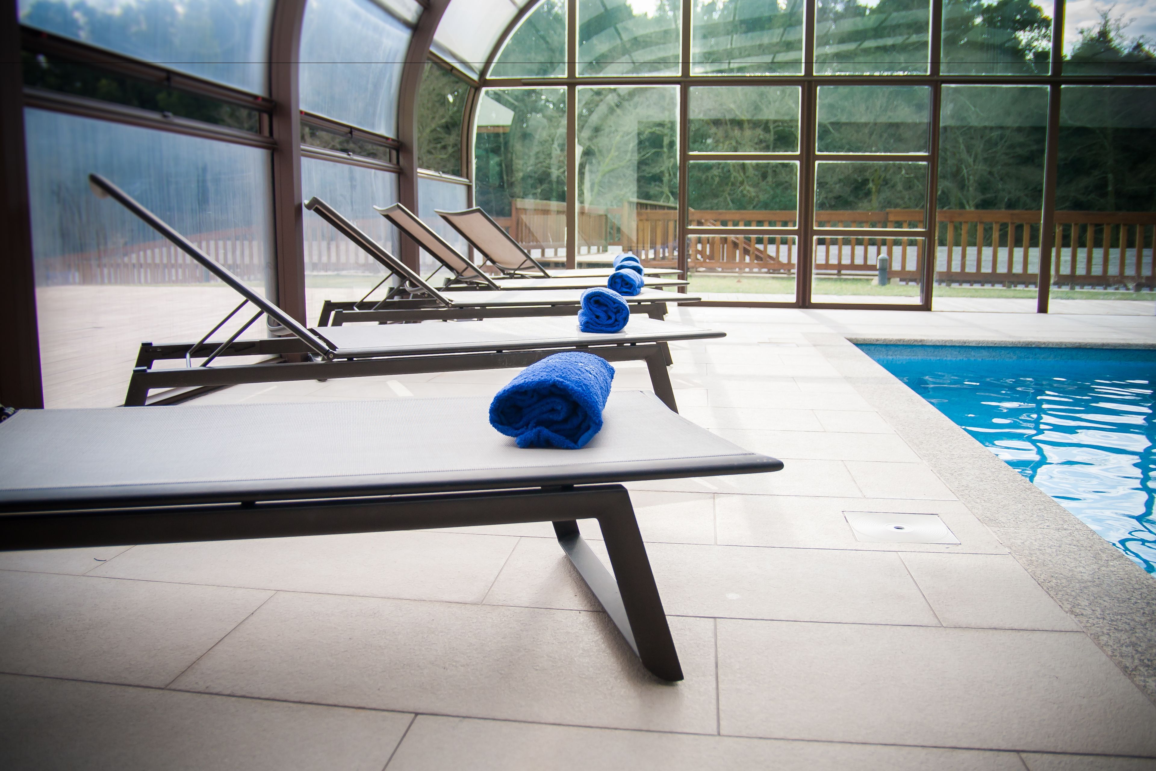 Uma área à beira da piscina com espreguiçadeiras e toalhas.