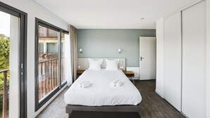 Quarto de hotel moderno com uma cama grande, varanda e vista para a cidade.