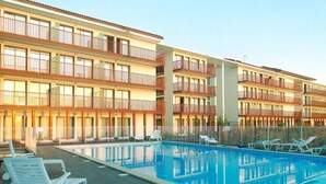 Um hotel com piscina, várias varandas e espreguiçadeiras.