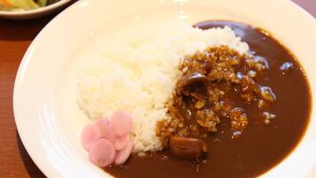 Um prato de arroz branco com molho marrom e acompanhamentos em conserva cor-de-rosa, servido em um prato branco.