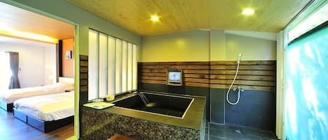 Quarto de hotel moderno com teto de madeira, uma cama grande, um pequeno espaço de estar, hidromassagem integrada e chuveiro.