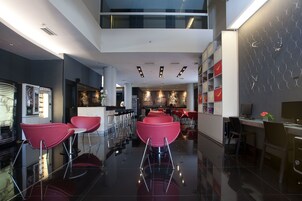 Um interior moderno com área de bar, cadeiras vermelhas e cozinha ao fundo.