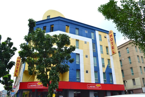 Um hotel de vários andares com fachada amarela, azul e branca.