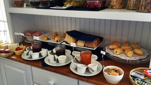 Buffet com diversos itens de comida, incluindo frutas, doces e acompanhamentos.