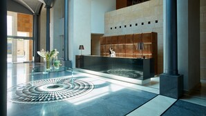 Um lobby moderno com balcão de recepção, mesa de centro de vidro e piso estampado.
