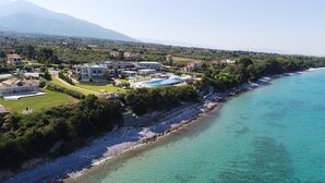 Um resort costeiro com vários edifícios, piscina e costa rochosa.