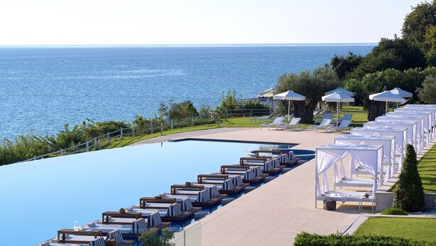 Piscina infinita com espreguiçadeiras e guarda-sóis com vista para o mar.
