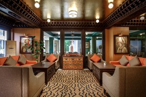 Um hall com carpete estampado, móveis de madeira e espelhos decorativos.